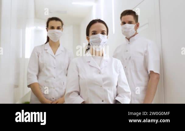 Three doctors take off their masks and pose for a camera at a new ...