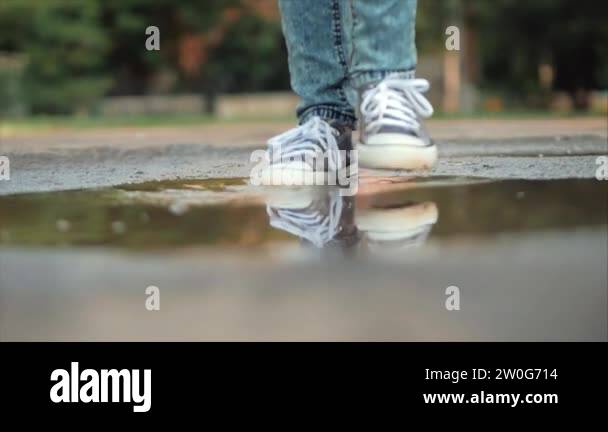 Low angle, close-up, unrecognizable kids running through puddles summer ...