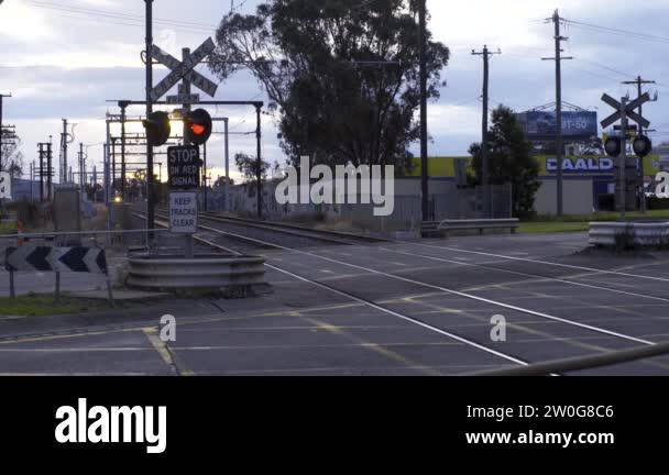 A railroad crossing with the gate closing as a commuter metro train ...