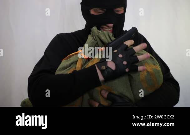 young caucasian thief in balaclava with a smirk and pleasure embracing ...