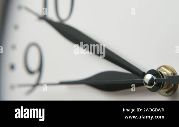 White clock face with three sharp black hands showing ten minutes to ...