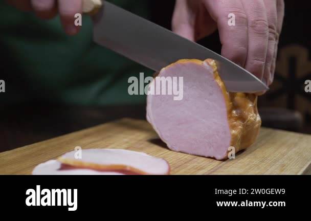 Close up video of tasty natural ham is sliced by sharp knife on the ...