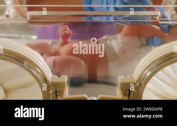 Infant in medical couveuse in maternity home. shot through glass ...