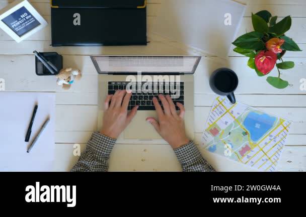 Male arms typing text on laptop keyboard at white wooden desk ...