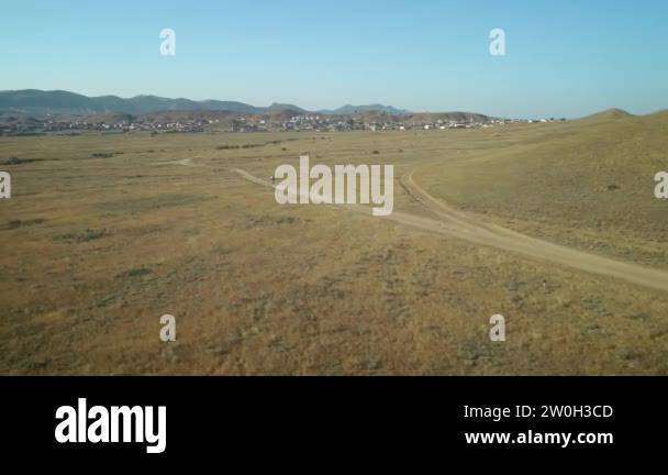 AERIAL: motorcycle rider rides on the sandy ground in the desert ...