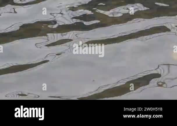 The flow of the river with the waves and the reflection of the bridge ...
