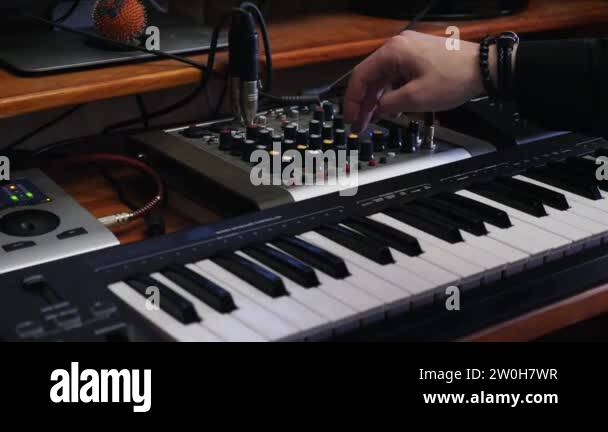 Sound producer pushes buttons and turning knobs on mixing board with ...