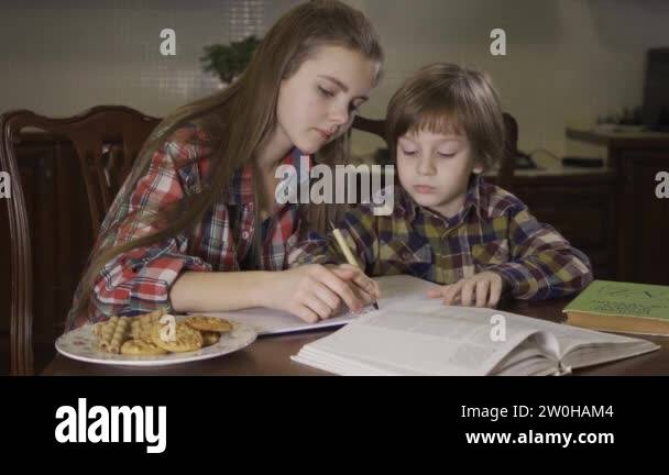 Older sister and younger brother doing homework together sitting at the ...