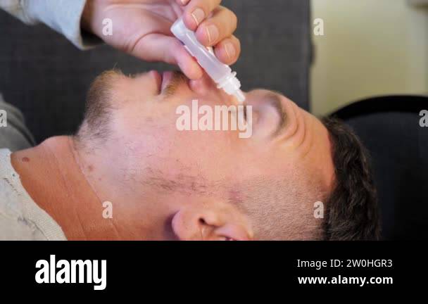 Close-up view of man who applying eye drop medicine healing. Young guy ...