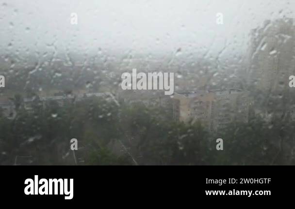 Heavy storm rain in the city through window. Rainy street and falling ...