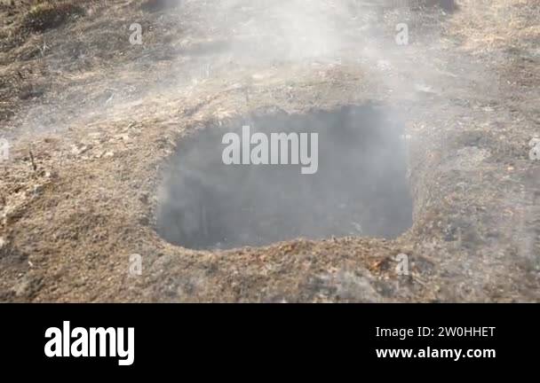 Burnt hole in the ground. Spring fire on the field. Ecological disaster ...