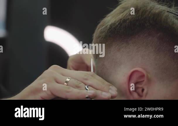 Barber cuts the hair of the client with scissors. Close up. Attractive ...
