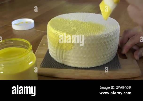 The cheesemaker covers the white cheese head with a yellow protective ...