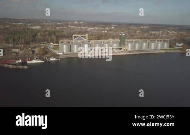 Grain elevator in the port on the river bank. Huge stainless steel ...