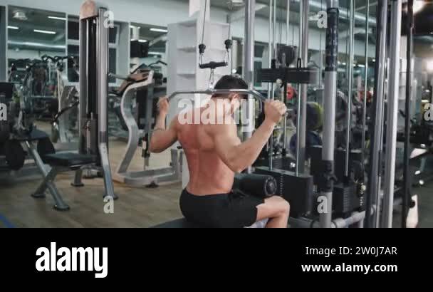 Bodybuilding man exercises his back muscle and triceps in the gym class ...
