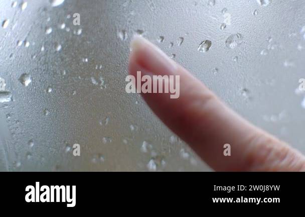woman draws a finger on the misted glass symbol of love heart in the ...