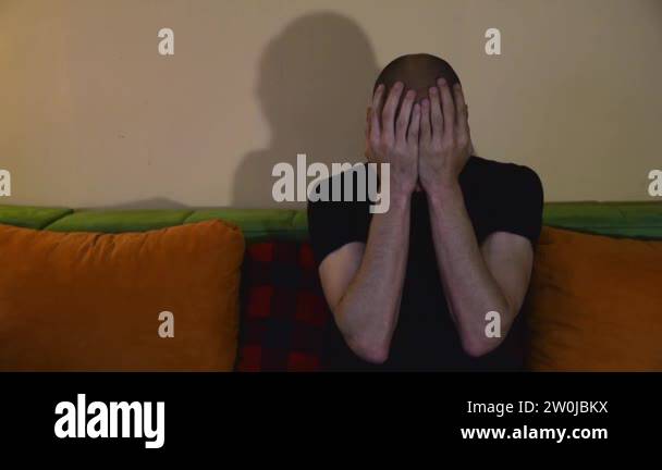 Young sad and depressed man sitting on his bed covered his face with ...