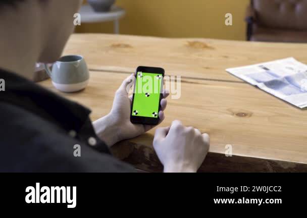 One guy holding in arms electronics gadget with green screen chromakey, scrolling and tapping it ...