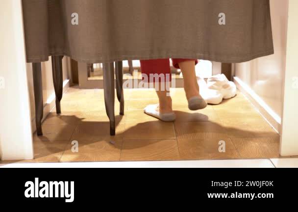 female legs are visible from under the curtains in the fitting room of ...