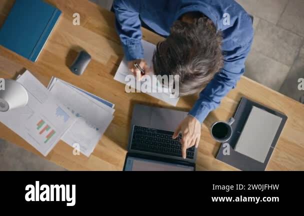 Businessman Sitting at His Desk in the Office Uses Laptop Computer ...