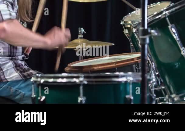 Young male drummer with long hair passionately playing on the drums and ...