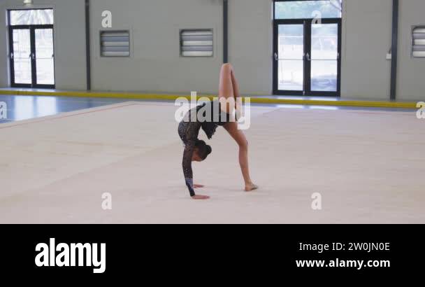 Side view of a focused teenage mixed race female gymnast performing at ...