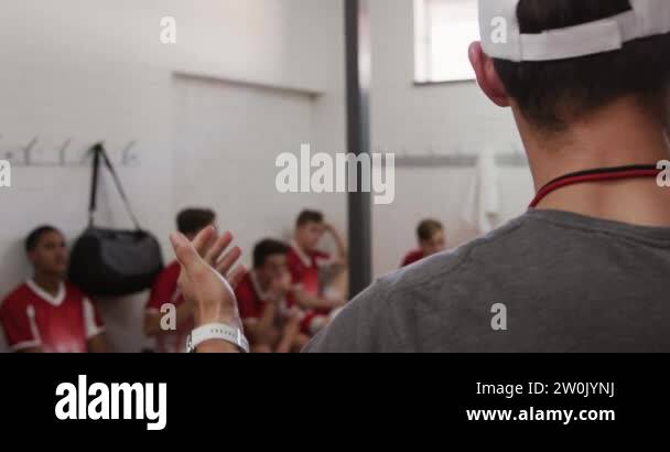 Rear view of a Caucasian male rugby coach standing in the changing room ...