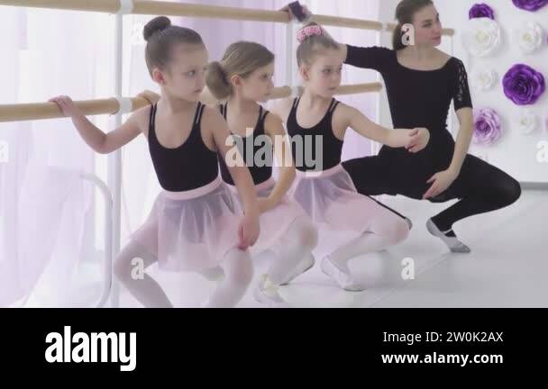 Concentrated girls are learning basic ballet positions in dancing ...