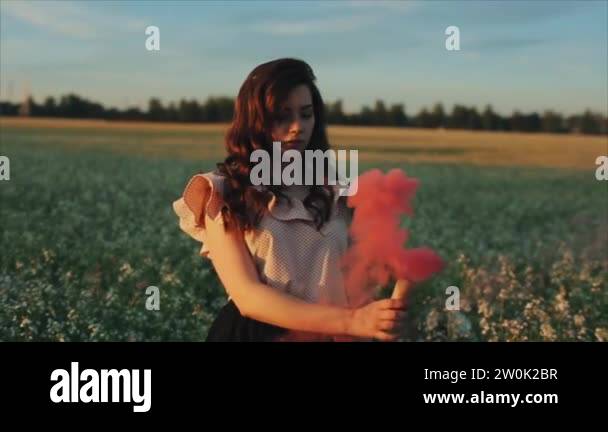 Young attractive brunette girl in skirt with a pink smoke bomb on the ...