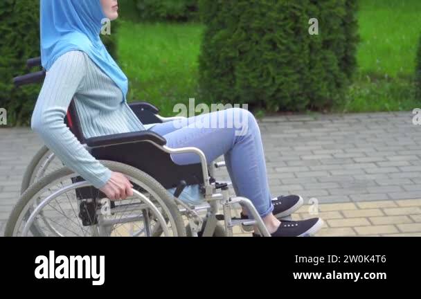 positive young disabled woman in a Muslim hijab stroller on a walk in ...