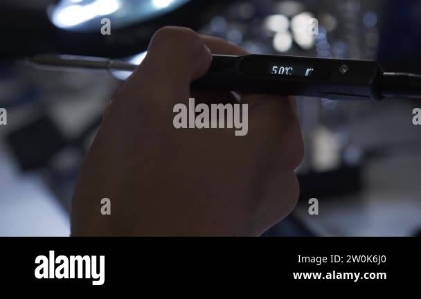 Young man working with modern soldering iron at his working place. The ...