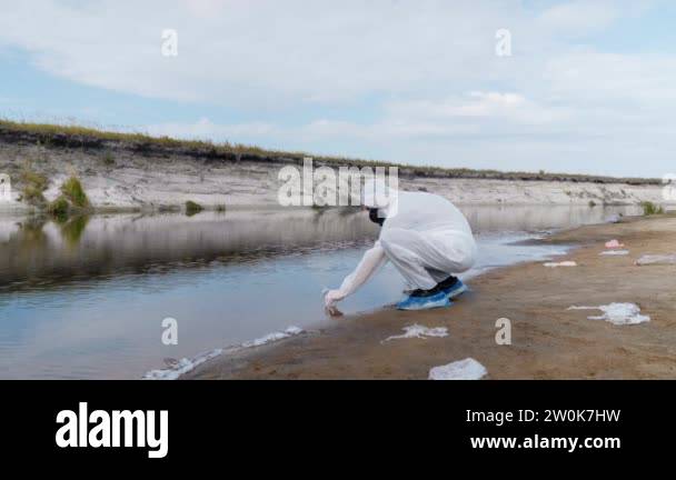 Man in a protective costume and gas mask of respirator observes a ...