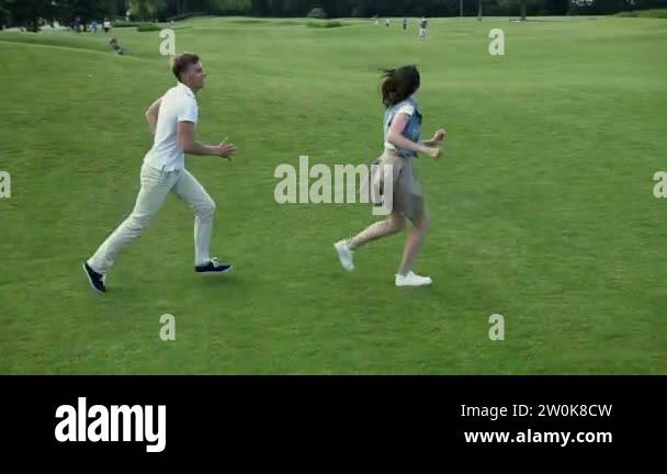 Man running after a girl on grass. The girl runs away from a guy. The ...