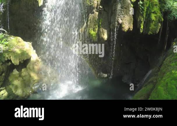 Water falling from the rocks and making a small rainbow on the water ...