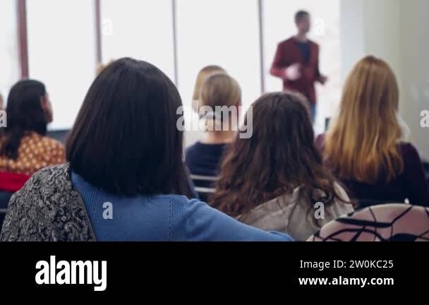 Audience listens to the lecturer at the conference hall. Backside view ...