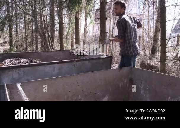 Spring work in local garden. Farmer turning compost heap to aerate and ...