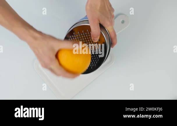 confectioner cuts the orange peel, citrus zester grating peeling orange ...