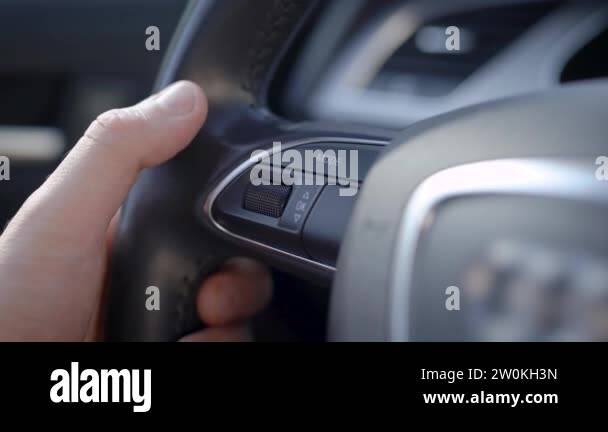 man is adjusting radio by buttons on steering wheel of modern car ... man is adjusting radio by buttons on steering wheel of modern car ...