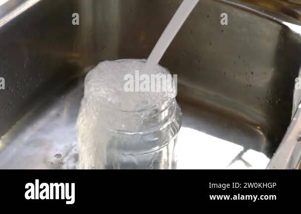 Tap Water Flowing To Container And Overflows To Sink Water Wastage Or