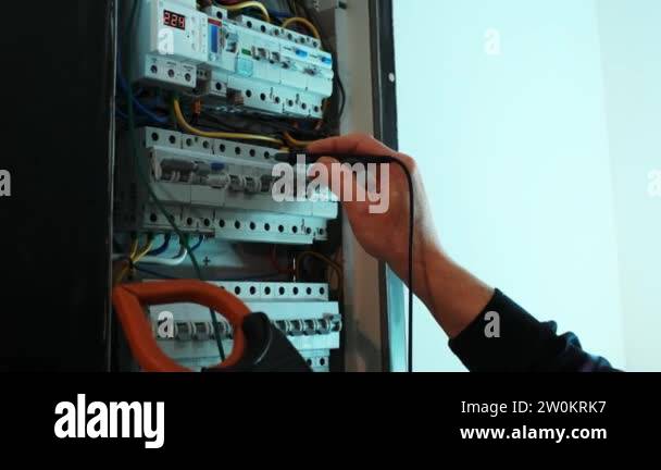 Electricians hands testing current electric in control panel ...