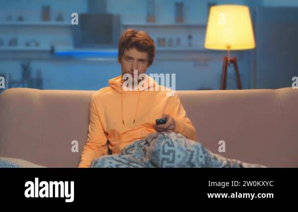 sleepy man watching tv, using remote controller and falling asleep ...