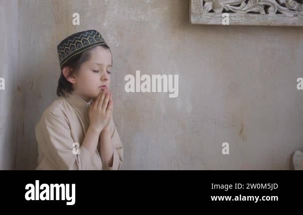 Adorable little kid in prayer hat and arabic clothes praying to Allah ...
