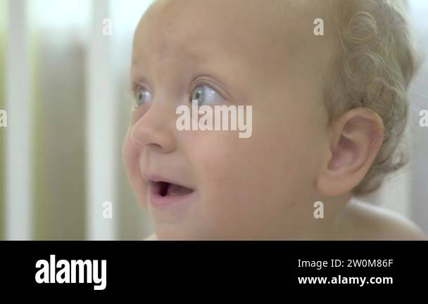 The baby looks puzzled look around. Baby laughing closeup. Baby sitting ...