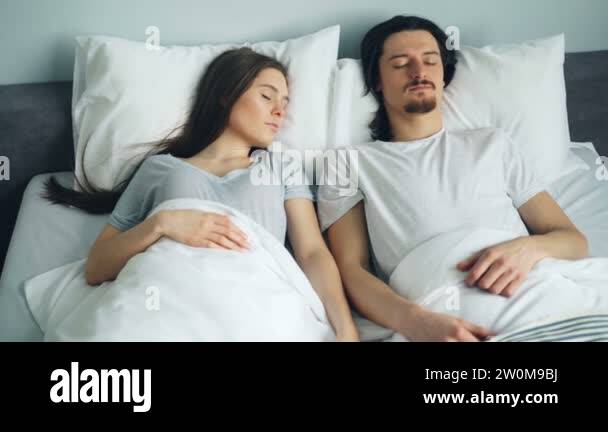 Young attractive man and woman sleeping in bed at home resting together ...