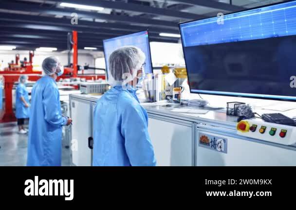 Technicians control the work of robotic equipment. Backside view of ...