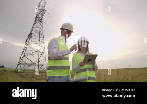 Engineer and supervisor with tablet PC and the drawings are about lines and transmission towers ...