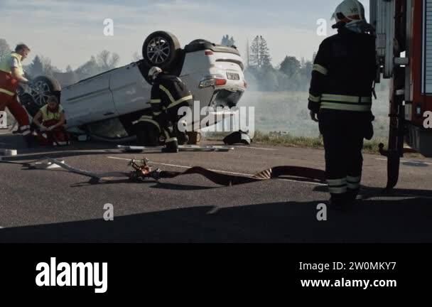 Rescue Team of Firefighters and Paramedics Work on a Terrible Car Crash ...