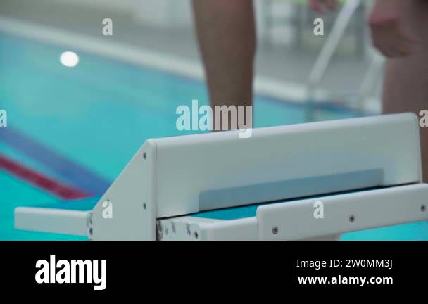 Professional sporty male swimmer jumping off into the swimming pool ...