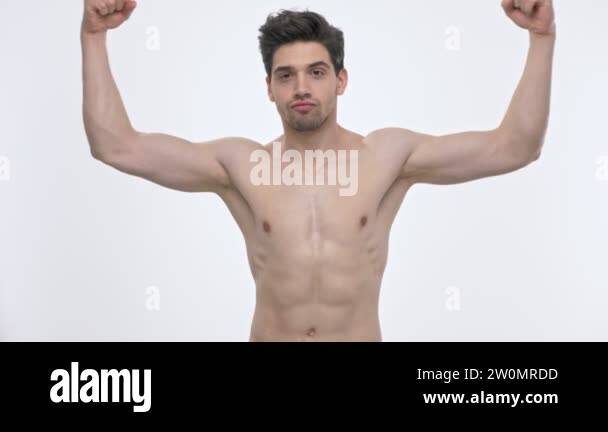 Confident young brunette man with naked torso showing his biceps with ...