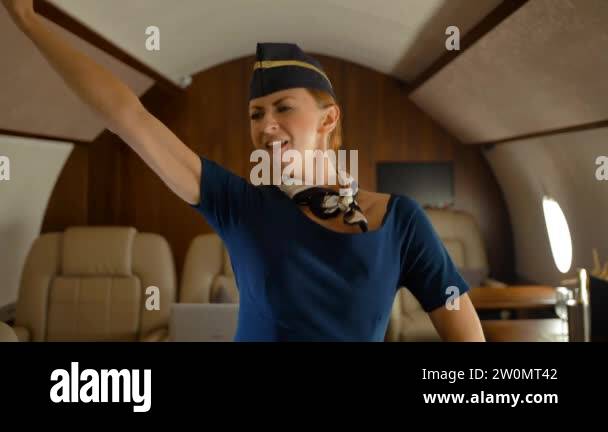 Stewardess joyfully dancing inside of private jet cabin, during flight ...
